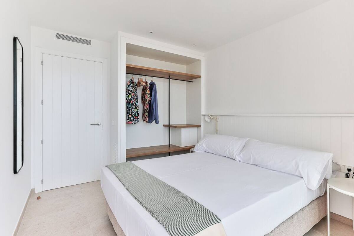 Quarto com cama, mesa de cabeceira, guarda-roupa e espelho.