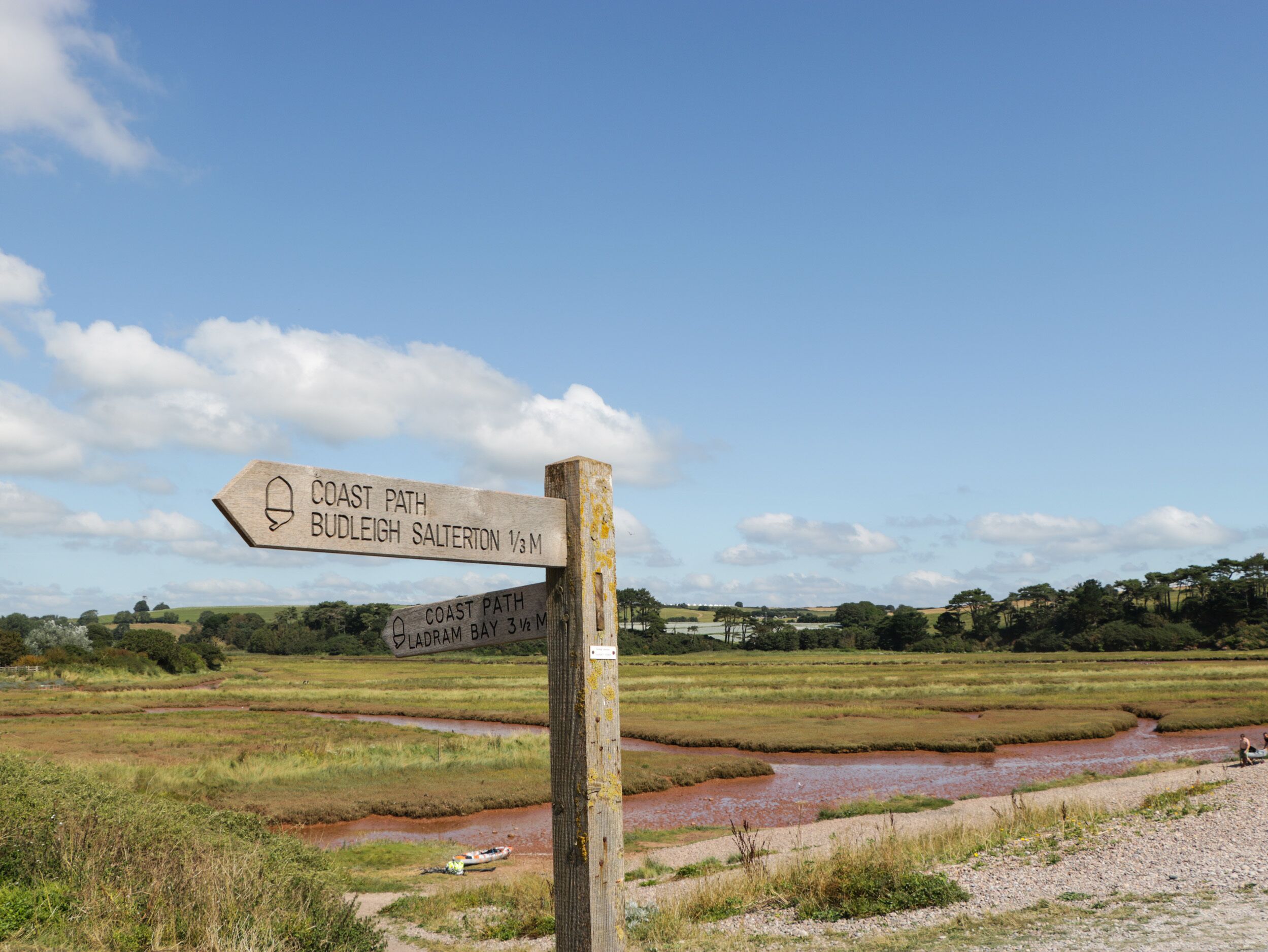 Um sinal de madeira com indicações de direção para Budleigh Salterton e Ladram Bay.