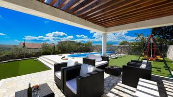 Um pátio externo com móveis de vime, piscina e vista para a paisagem.