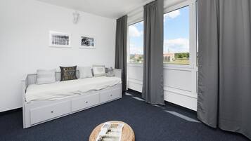 Quarto de hotel moderno com uma cama, uma mesinha e vista para o exterior.