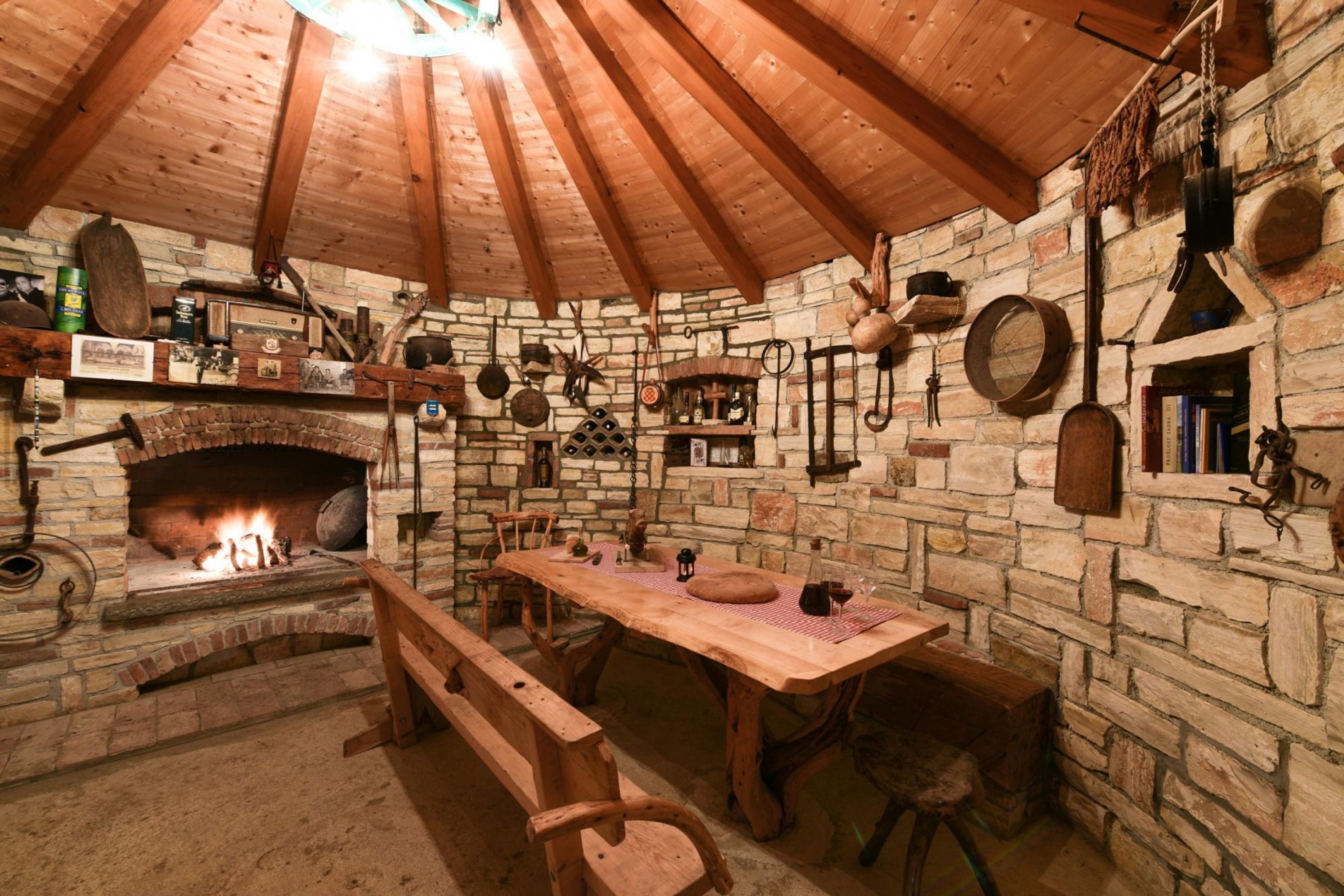 Um quarto rústico com lareira de pedra, vigas de madeira e uma mesa de madeira com bancos.