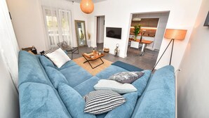 Uma sala de estar moderna com um sofá azul, uma mesa de centro e uma televisão.