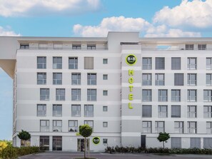 Um hotel moderno com vários andares, janelas amplas e uma placa B&B Hotels bem visível.