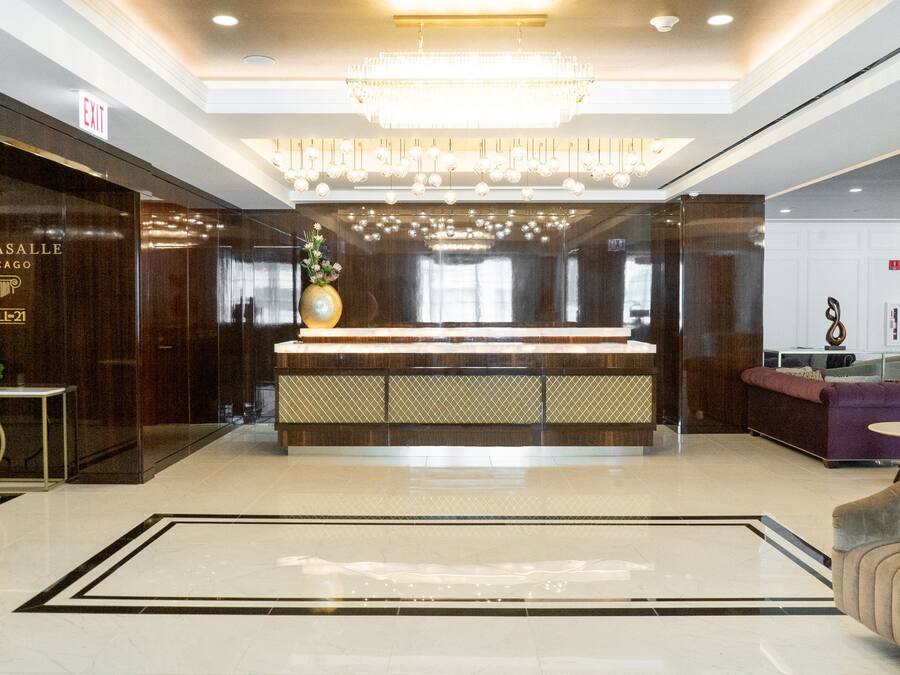 Um hall de hotel com uma receção, um candelabro, um sofá e um vaso decorativo.