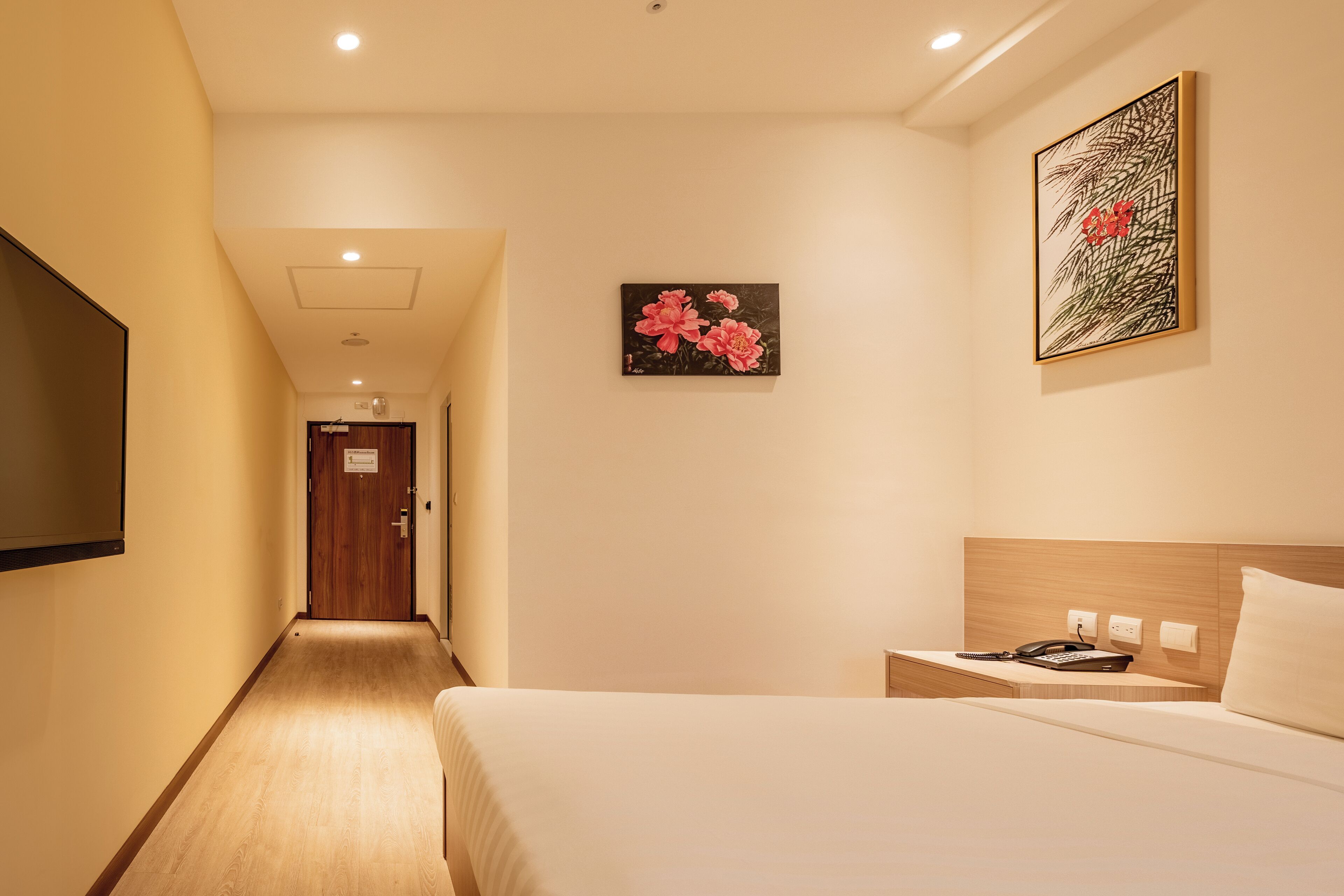 Quarto de hotel com cama, mesa de cabeceira e uma obra de arte na parede.