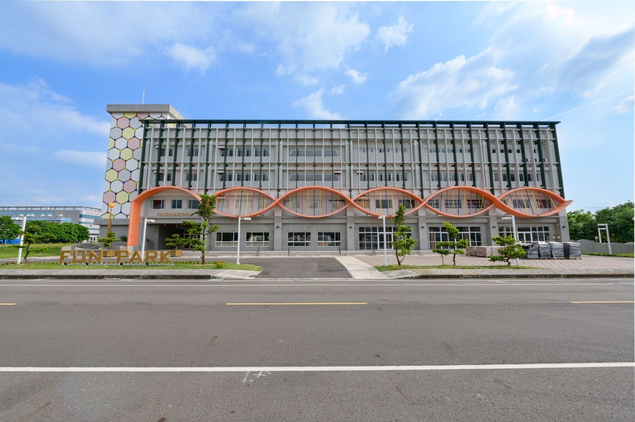 Um edifício moderno com fachada de vidro, uma entrada imponente com teto curvo e uma placa com a inscrição 