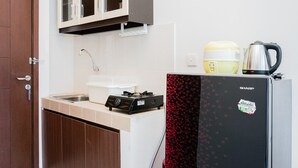 Uma cozinha compacta com pia, fogão a gás, geladeira e micro-ondas.