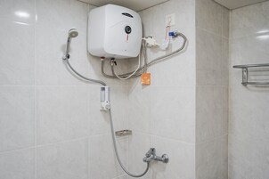 Uma casa de banho moderna com cabine de duche integrada, chuveiro manual e um acessório de duche de mão.