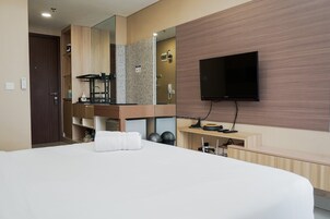 Quarto de hotel moderno com uma cama grande, televisão, espelho, pia e penteadeira de madeira.