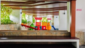 Uma área de recreação infantil com um conjunto de comboios colorido e um banco de azulejos.