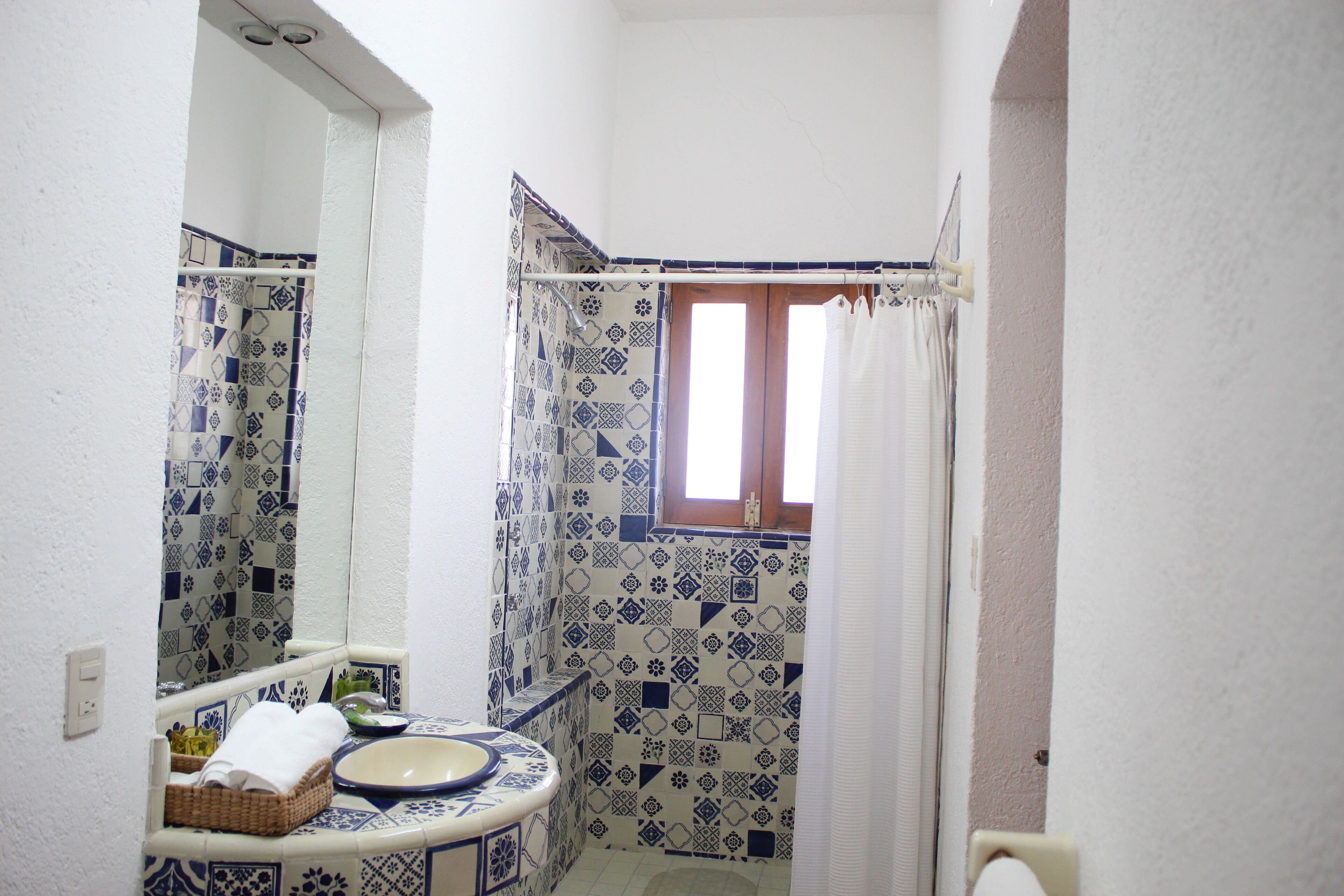 Um banheiro com pia, espelho e azulejos estampados.