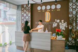 Um balcão de recepção de hotel com design moderno, apresentando um painel de madeira, um balcão e um relógio.