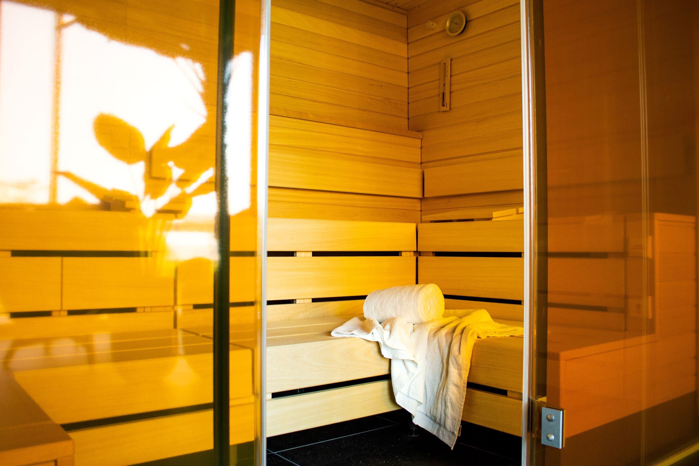 Uma sala de sauna com bancos de madeira e porta de vidro.