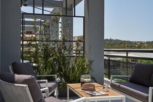 Varanda com vista, mobiliada com uma mesa, cadeiras e um vaso de planta.