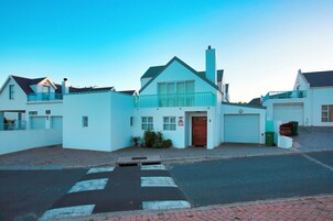 Uma casa moderna de dois andares com garagem, varanda e um pequeno jardim.