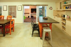 Uma cozinha com mesa de jantar, cadeiras, um banquinho e armários.