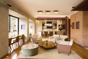 Uma sala de estar moderna com uma mesa de centro redonda, sofás e um espaço bar com prateleiras cheias de garrafas.