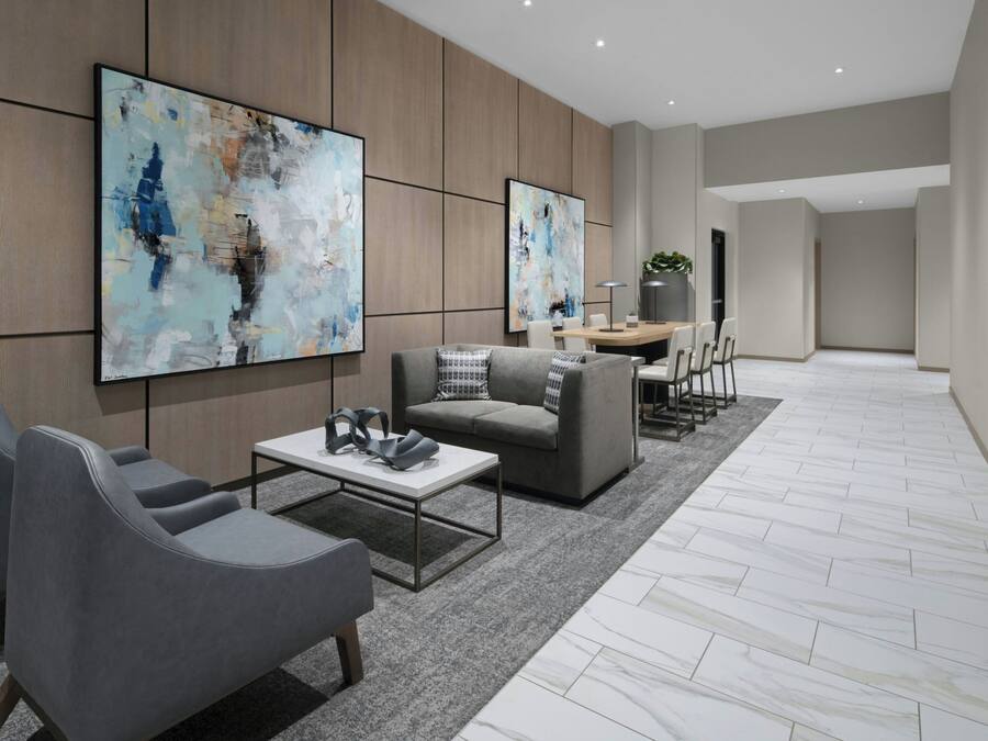 Uma área de estar moderna com sofá, poltronas, mesa de centro e quadros abstratos na parede.