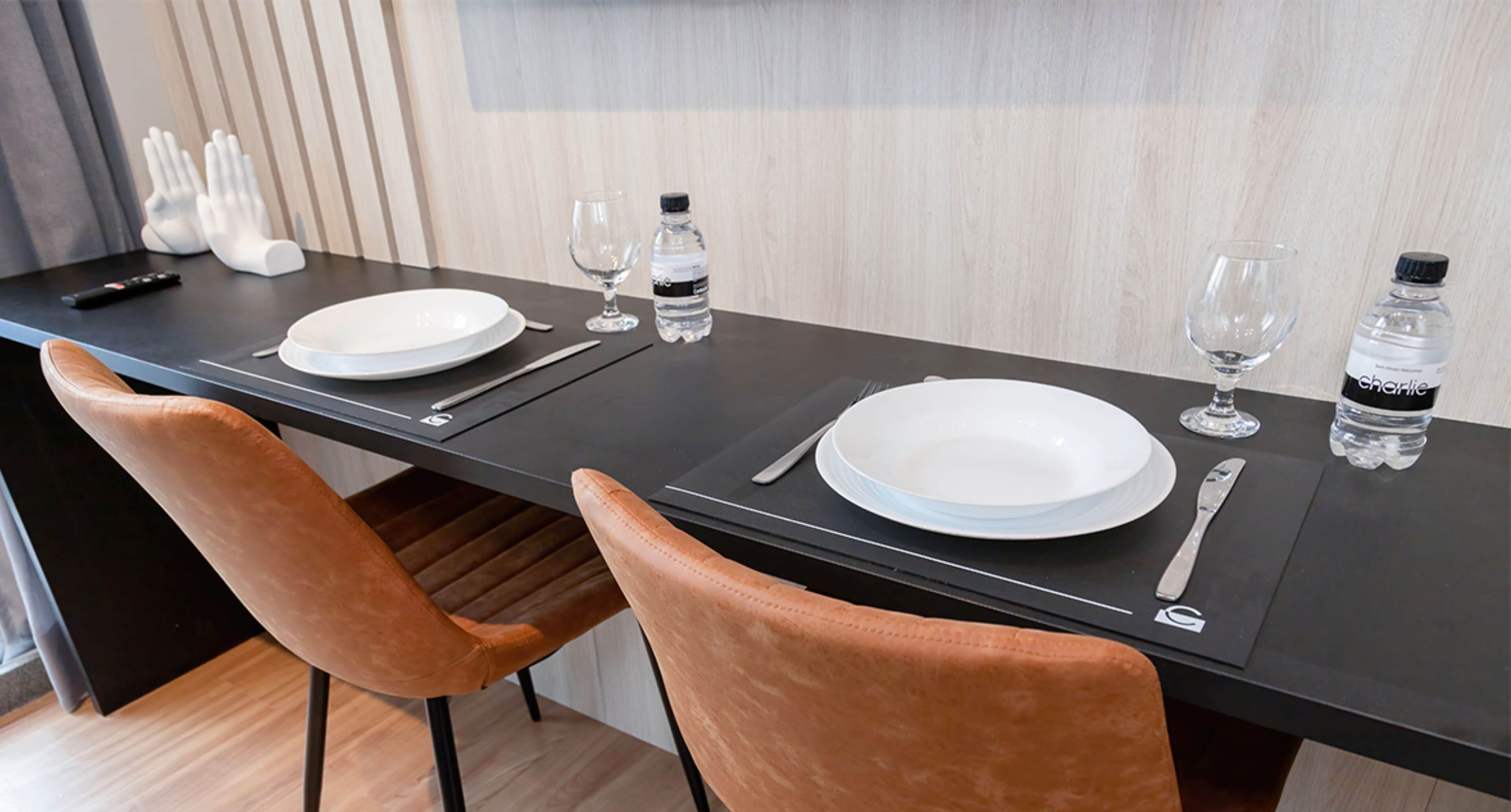 Mesa de jantar posta com pratos, talheres e garrafas de água.