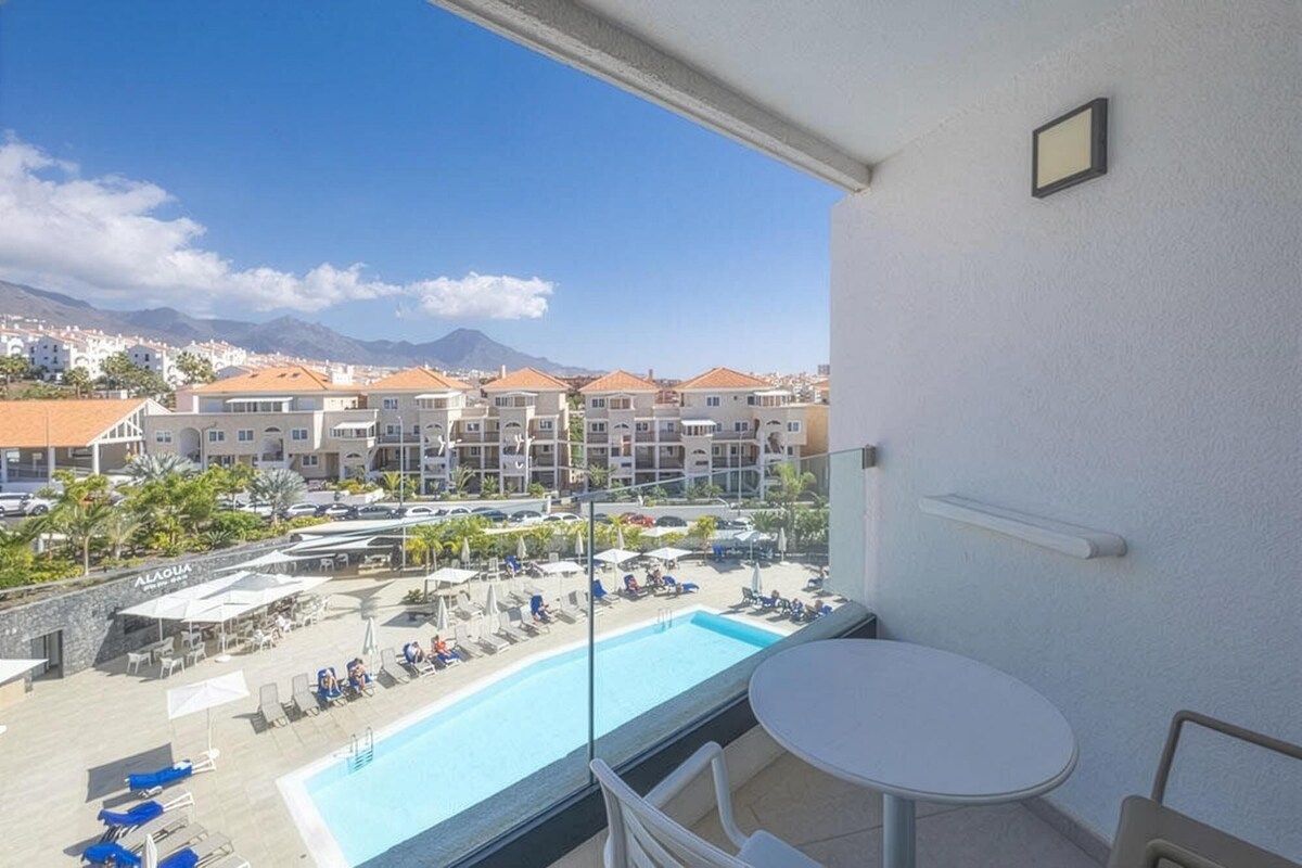 Uma varanda com vista para uma piscina, espreguiçadeiras e uma mesa.