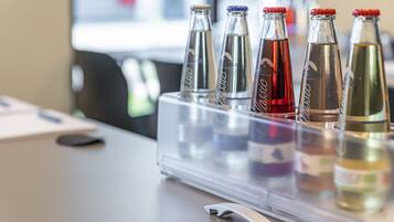 Suporte de plástico transparente para garrafas com diversas garrafas, incluindo Coca-Cola, sobre uma mesa.