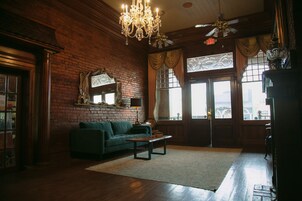 Um quarto com parede de tijolos, sofá verde, mesa de centro de madeira e um candelabro.
