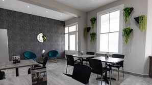 Uma sala de reunião moderna com paredes cinzentas, cadeiras pretas e um amplo janelão.