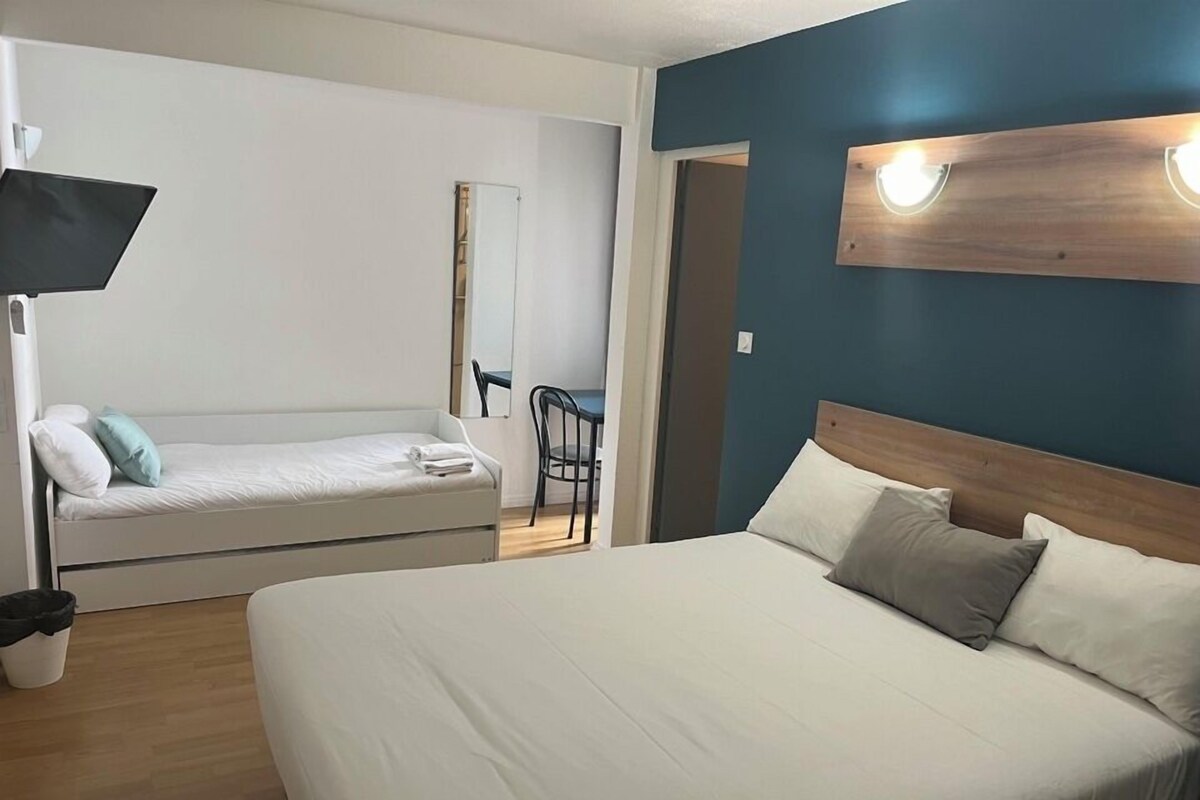 Quarto de hotel com uma cama grande, um sofá menor, uma escrivaninha e uma cadeira.