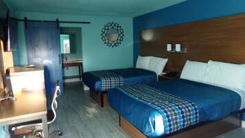 Quarto de hotel com duas camas, uma escrivaninha e uma cadeira.