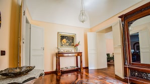 Um quarto espaçoso com assoalho de madeira, um espelho grande e ornamentado e um quadro na parede.