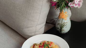 Um prato de comida sobre uma mesa, ao lado de um sofá e um vaso com flores.