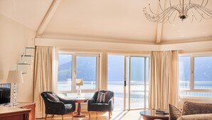 Uma sala de estar espaçosa com uma grande janela, um candelabro e vista para o mar.