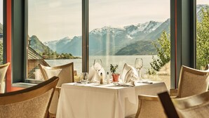 Mesa de jantar posta com vista para um lago e montanhas.