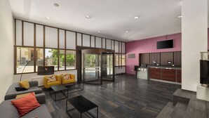 Um hall moderno com balcão de recepção, área de estar e amplas janelas.