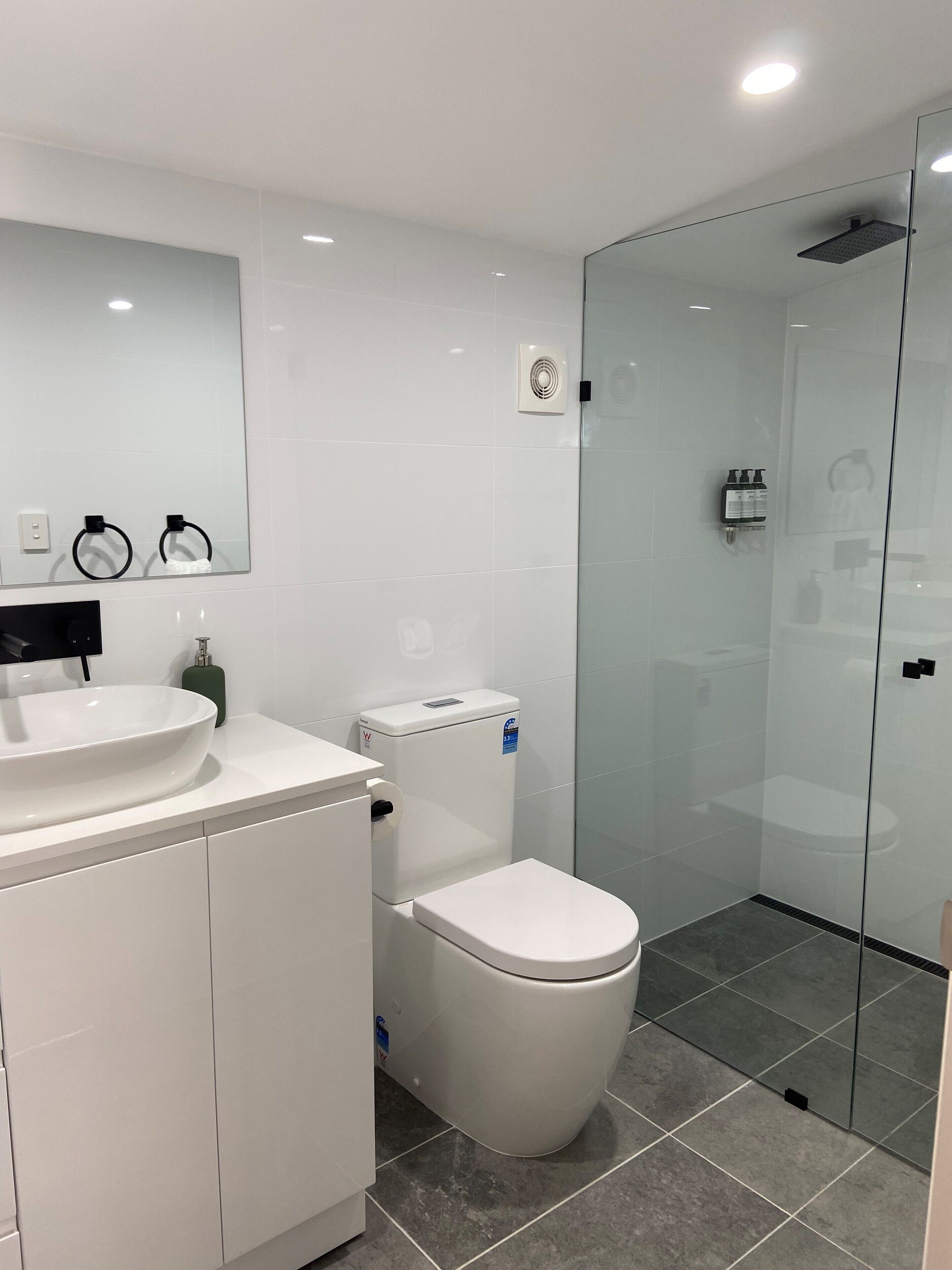 Uma casa de banho moderna com lavatório branco, sanita e cabine de duche em vidro.