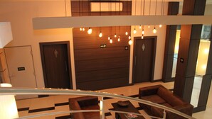 Um lobby moderno com escadaria, área de sofás e balcão de recepção.