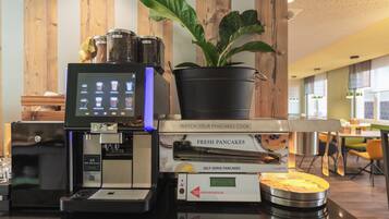 Máquina de café com visor digital e estação de panquecas para servir.