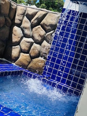 Piscina com azulejos azuis e uma parede de pedra.