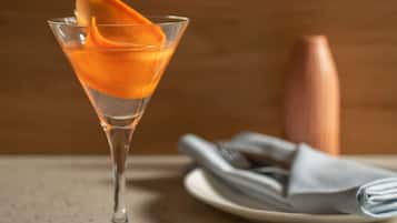 Um copo de cocktail com um enfeite de cítricos sobre uma mesa.