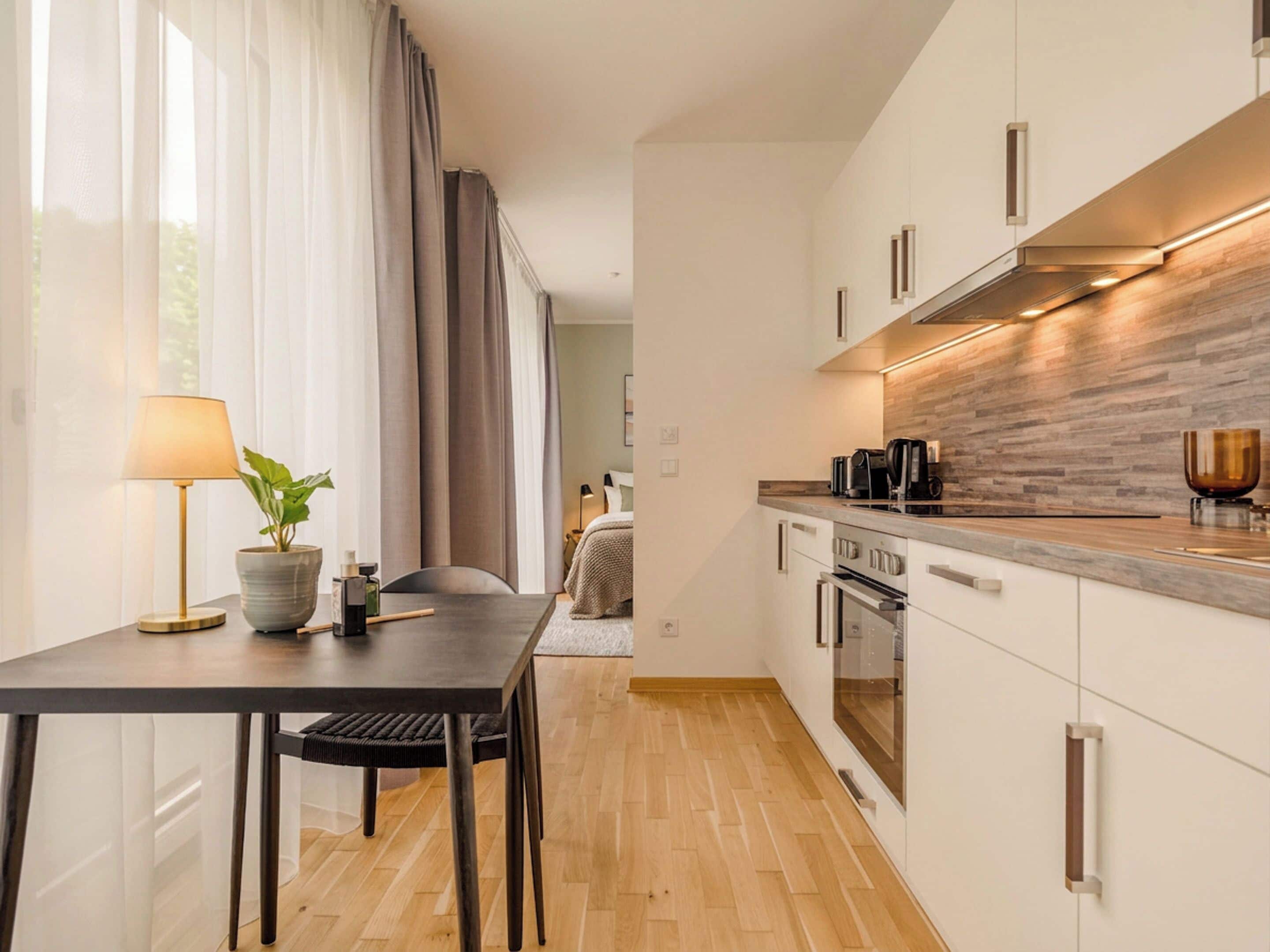 Uma cozinha moderna com área de jantar, piso de madeira e vista para a sala de estar.