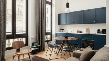 Cozinha moderna com armários azul escuro, uma mesa de jantar redonda e uma máquina de café.