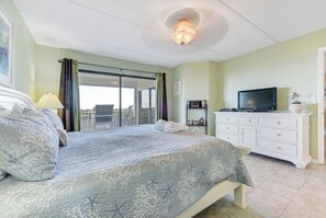 Quarto de hotel com uma cama, televisão, penteadeira e varanda com vista.