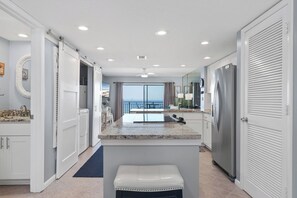 Cozinha moderna com uma ilha grande, armários brancos e vista para o exterior.