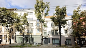 Vista da rua com uma fileira de edifícios altos, alguns com varandas e janelas visíveis.