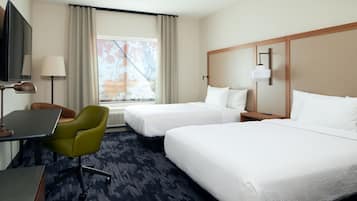 Quarto de hotel com duas camas, uma escrivaninha, uma cadeira, uma televisão e uma janela com cortinas.