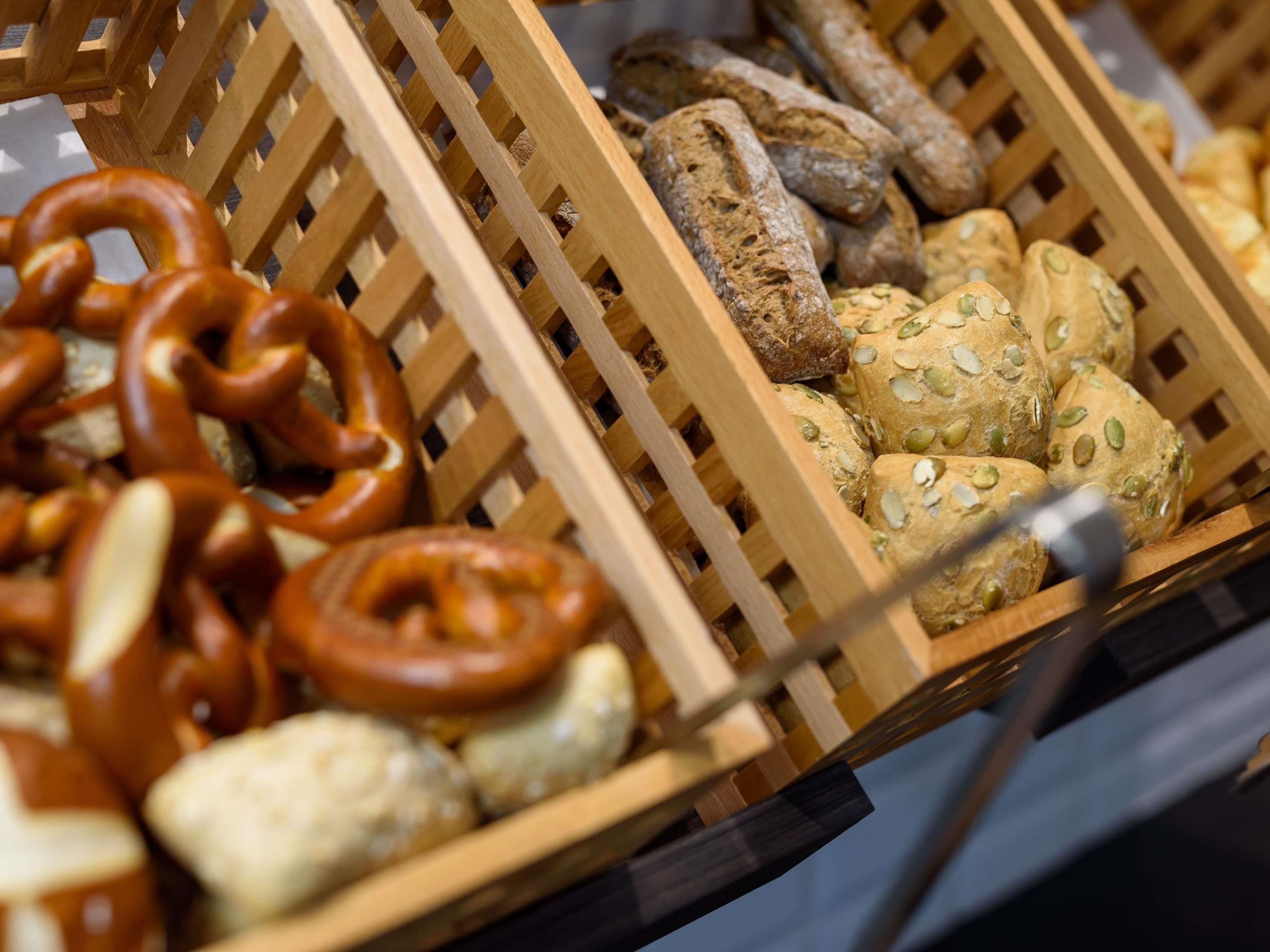 Uma cesta de madeira repleta de produtos de panificação variados, incluindo pretzels, pães e doces.