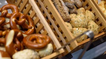 Uma cesta de madeira repleta de produtos de panificação variados, incluindo pretzels, pães e doces.