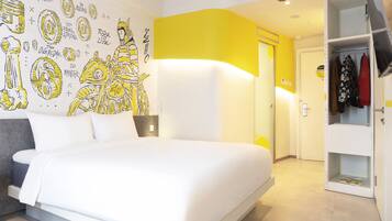 Quarto de hotel moderno com uma cama grande, um guarda-roupa e uma parede com desenhos motivacionais.