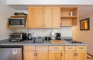 Cozinha compacta com armários de madeira, micro-ondas, torradeira, chaleira, máquina de café e pia.