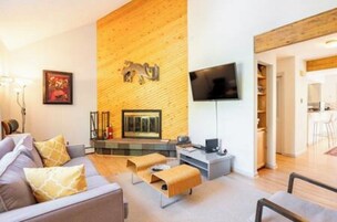 Uma sala de estar moderna com uma parede de destaque em madeira, uma TV de tela plana, um sofá e uma mesa de centro.